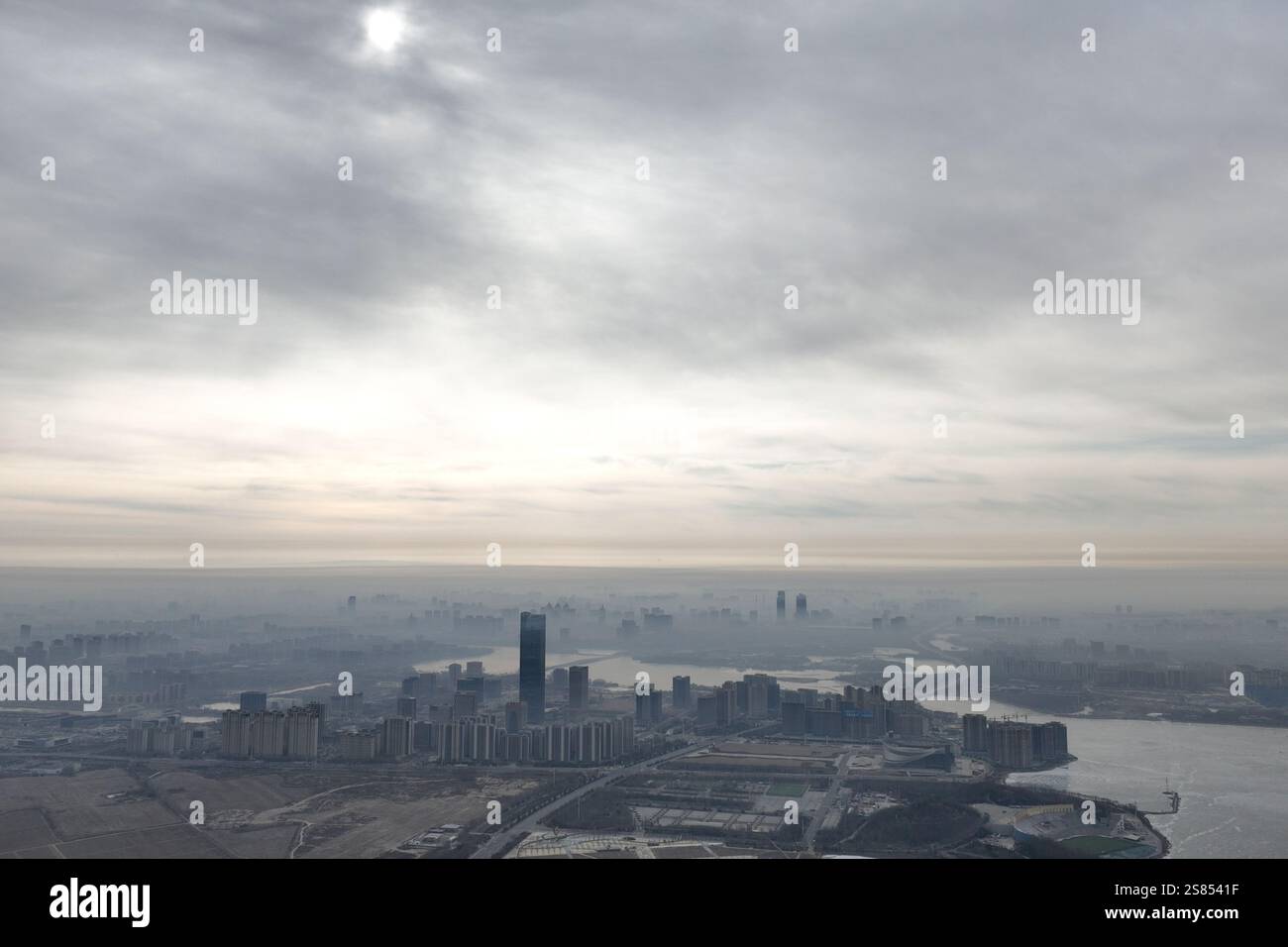 A cluster of urban buildings looms in the morning fog in Yinchuan city ...