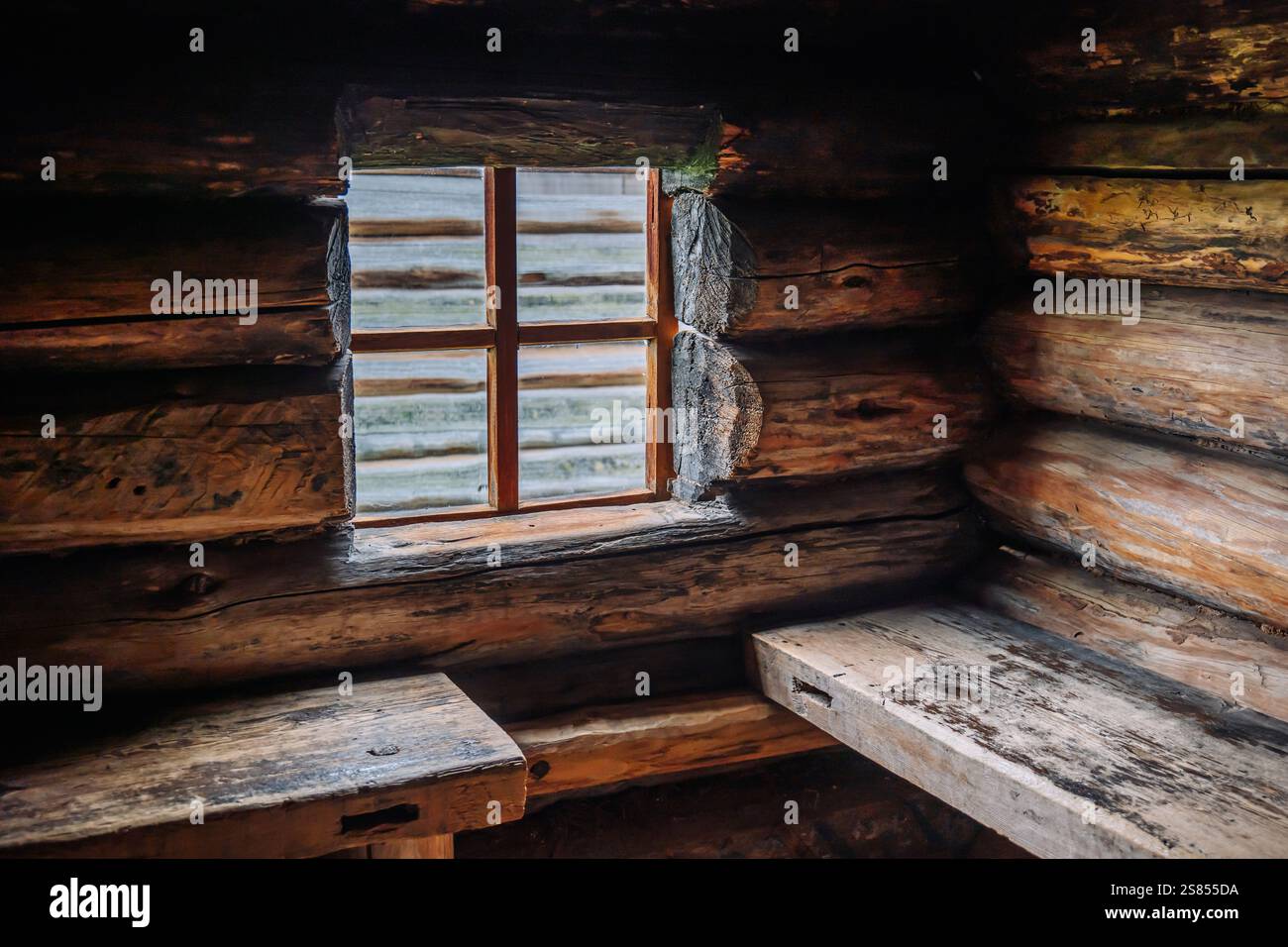 Light illuminating interior of rustic log cabin with wooden benches ...