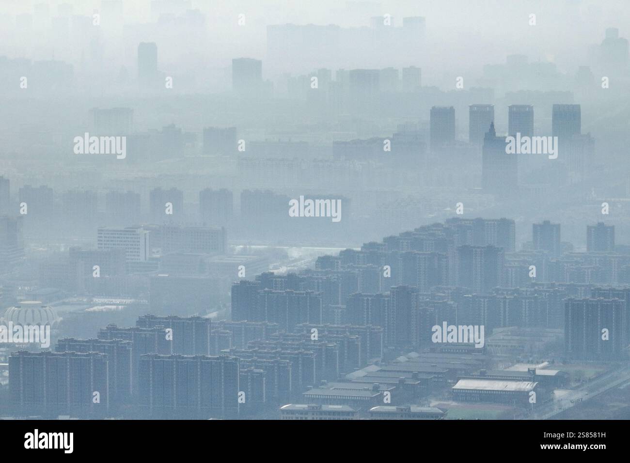 A cluster of urban buildings looms in the morning fog in Yinchuan city ...