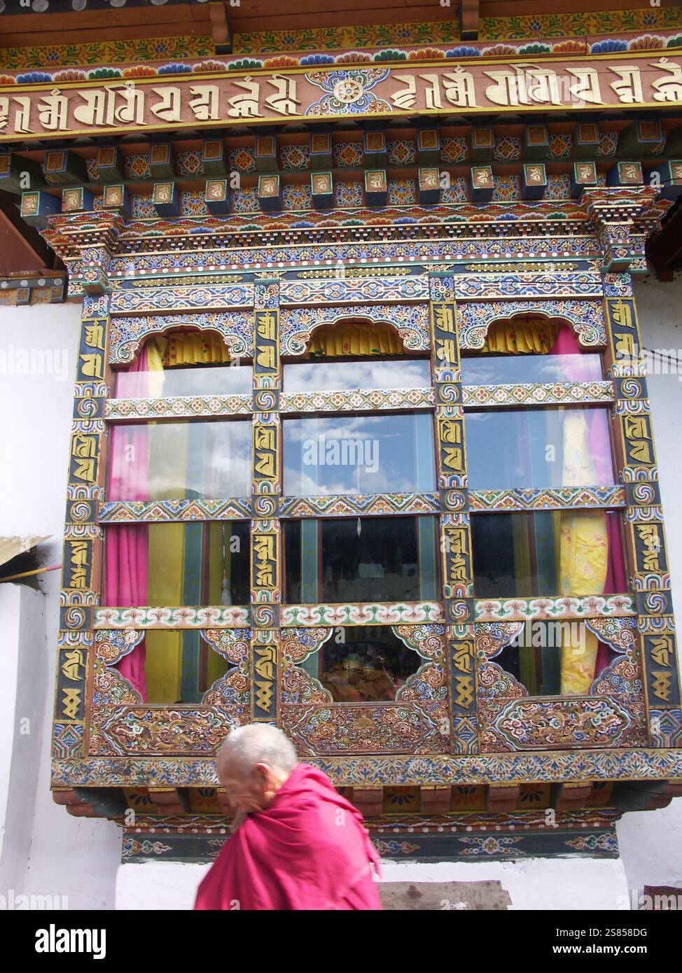 Buddhist monk walks past a window of monastery in Bhutan Stock Photo ...