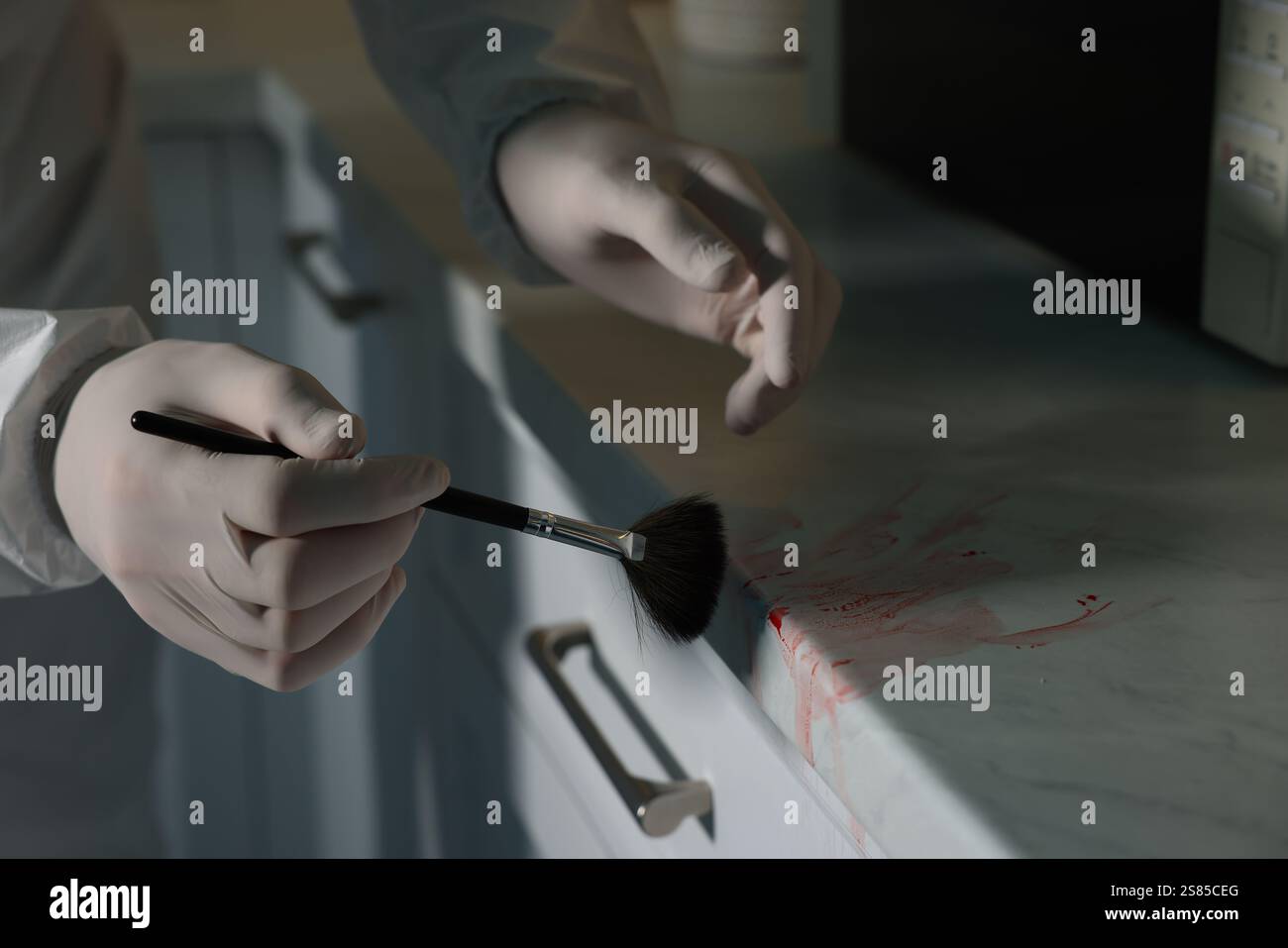 Forensic expert taking fingerprints from countertop with brush at crime scene indoors, closeup ...