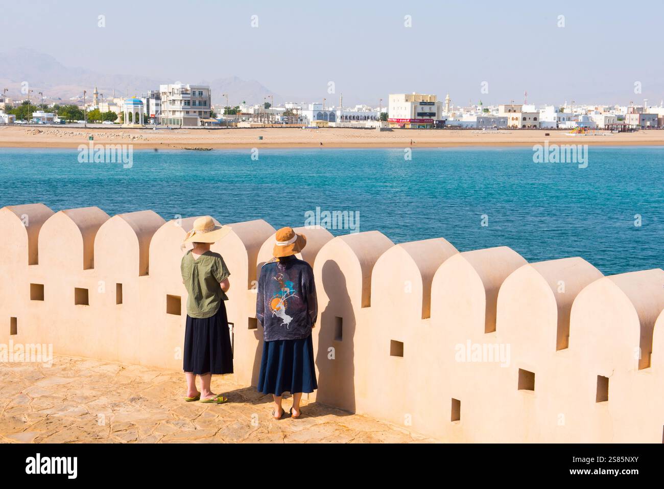 Two female tourists by crenelated wall of lighthouse, Al Ayjah village ...