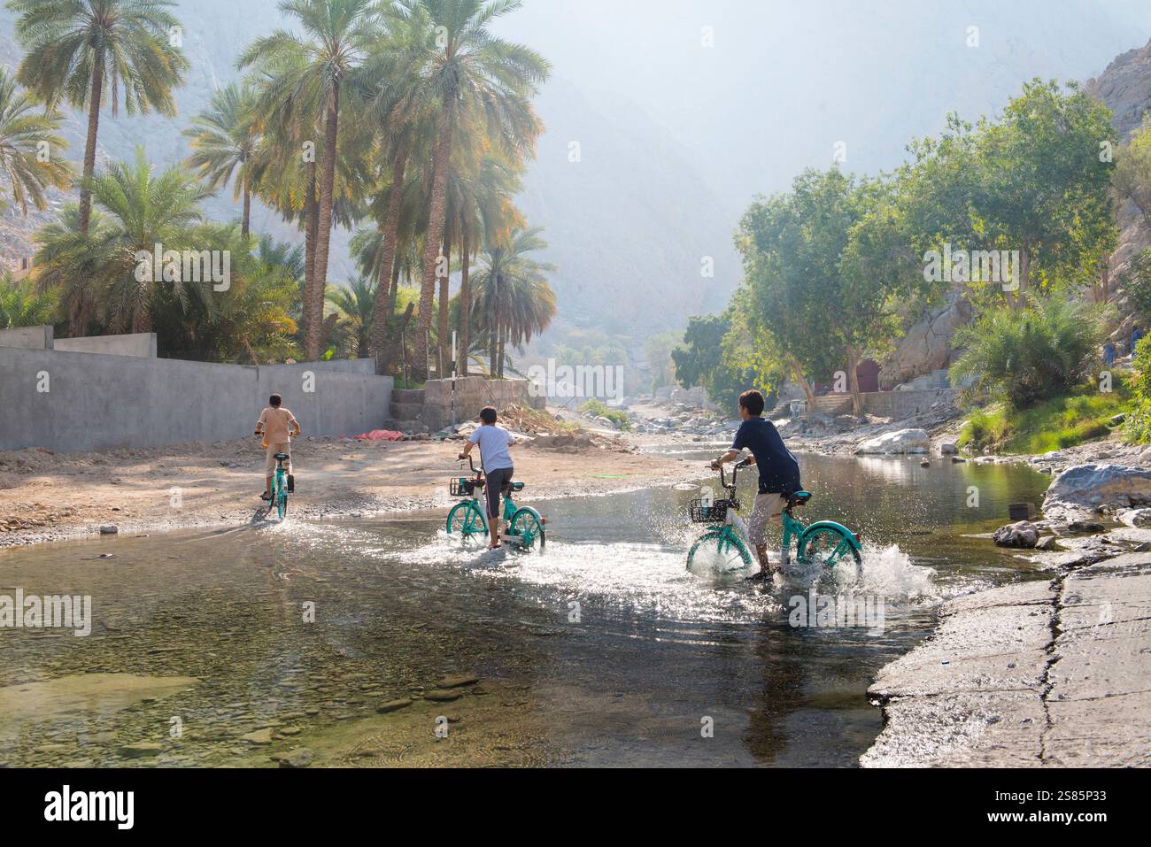 Kids on bicycles crossing the river near the Al Thowarah hot spring ...