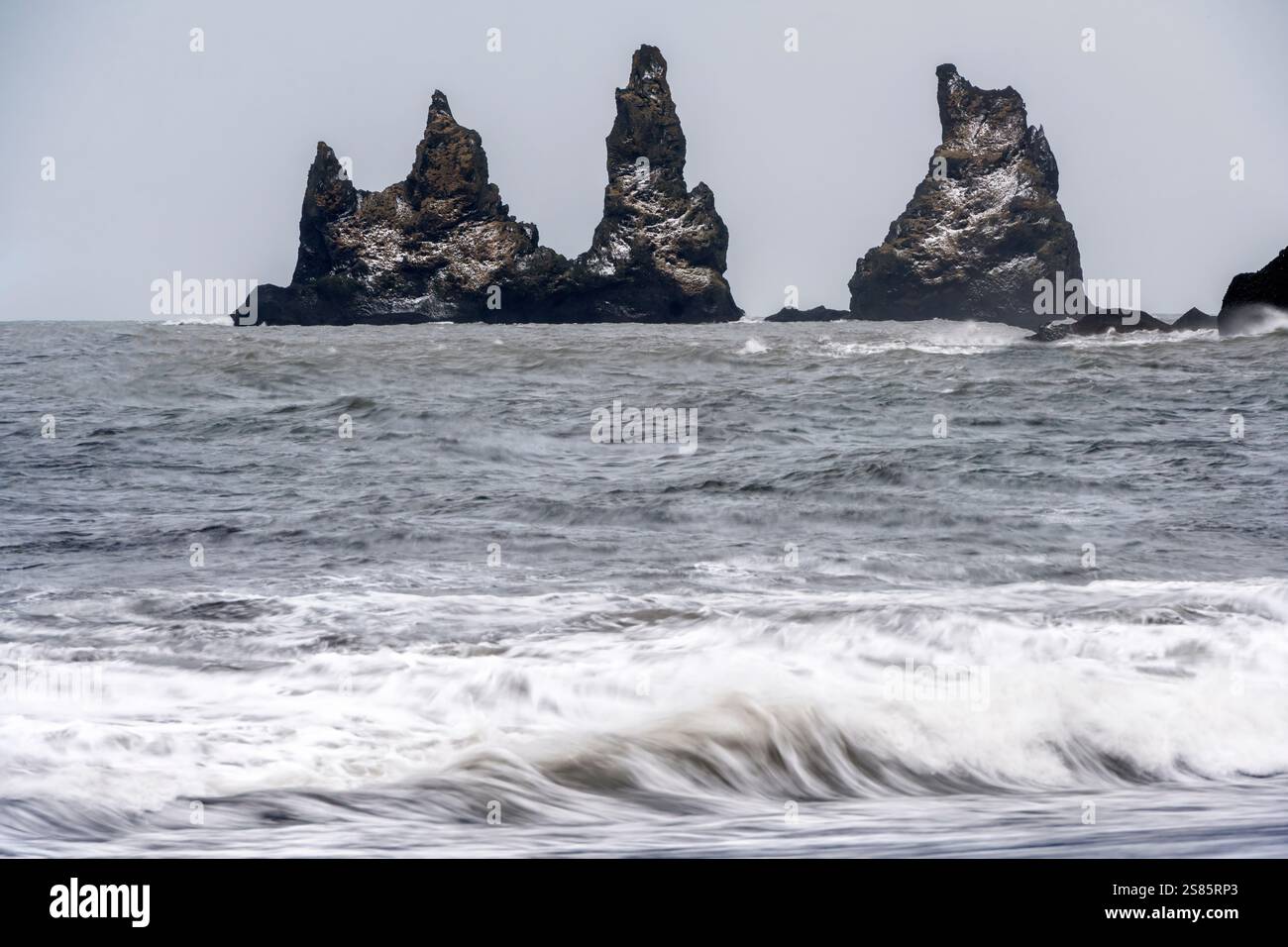 Panoramic view of ocean waves with protruding rocks from black sand ...
