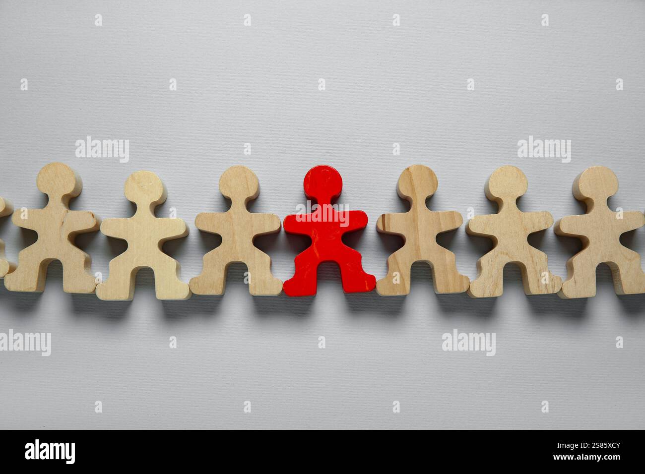 Personality concept. Red human figure among wooden ones on light grey ...