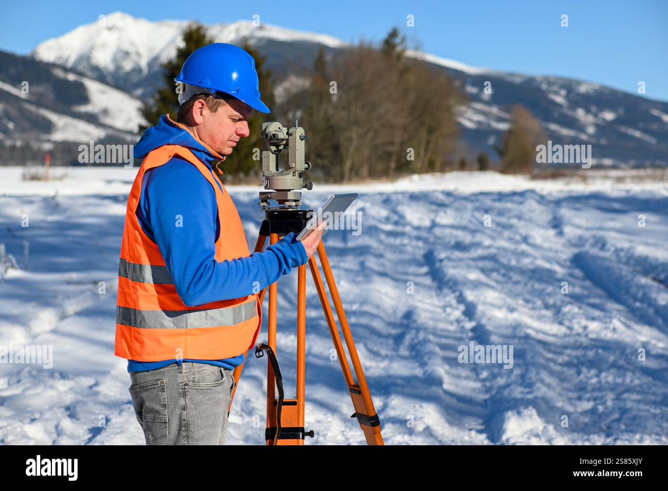 Surveyor taking measurements in snowy mountain landscape using ...