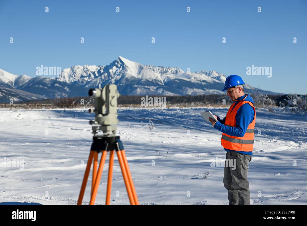 Surveyor taking measurements in snowy mountain landscape using ...