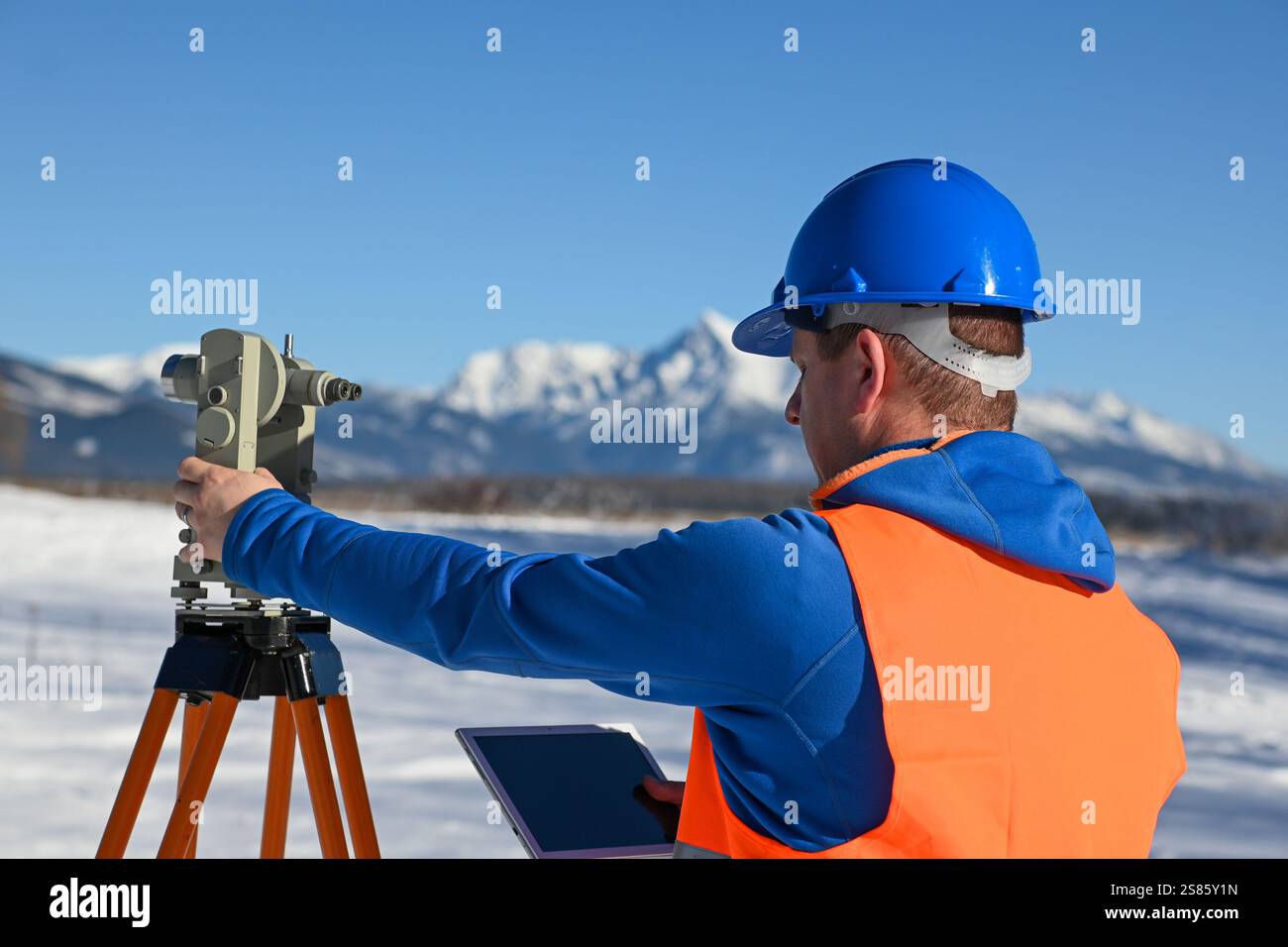 Surveyor taking measurements in snowy mountain landscape using ...