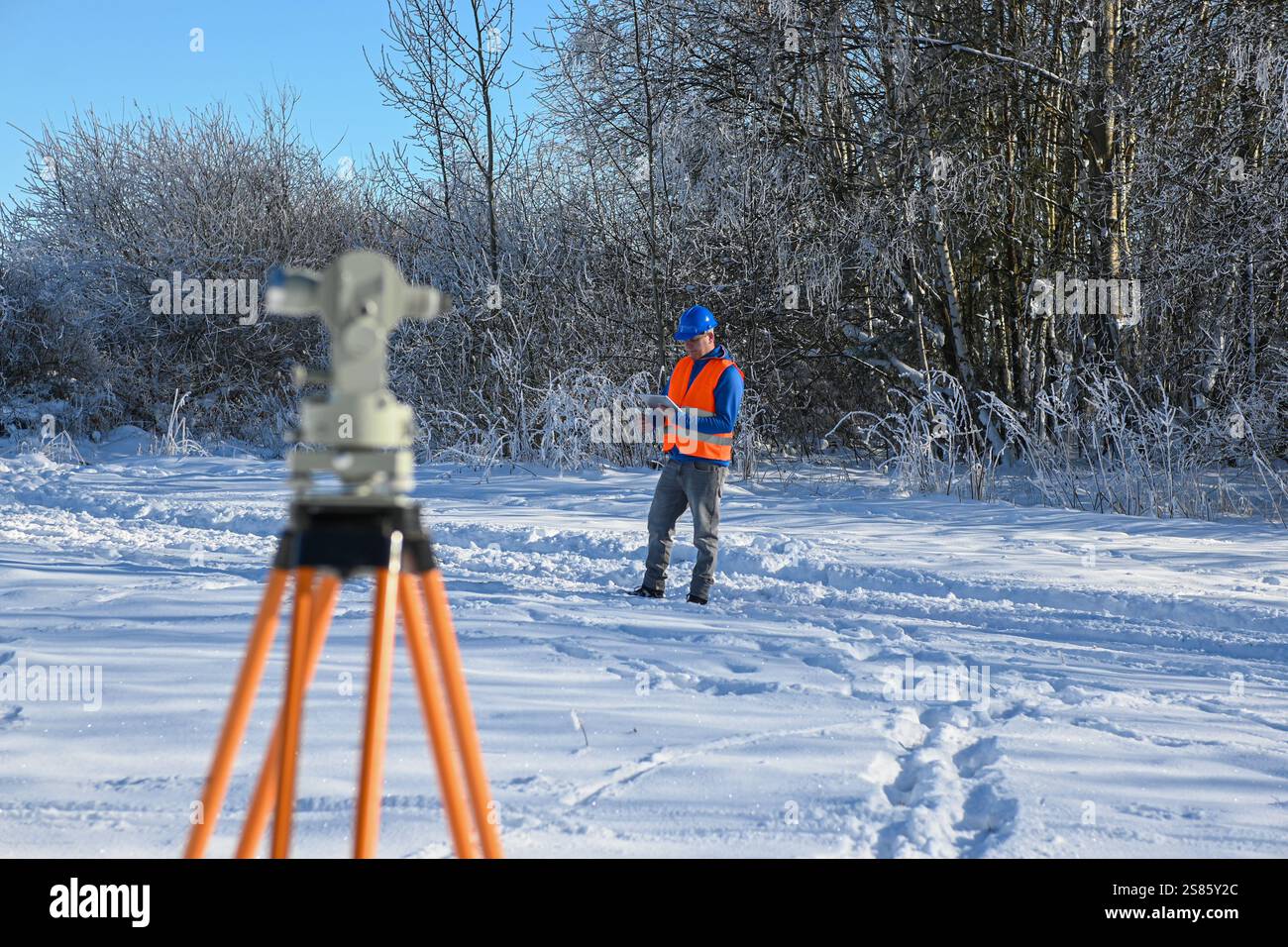 Surveyor taking measurements in a snowy field using a theodolite ...