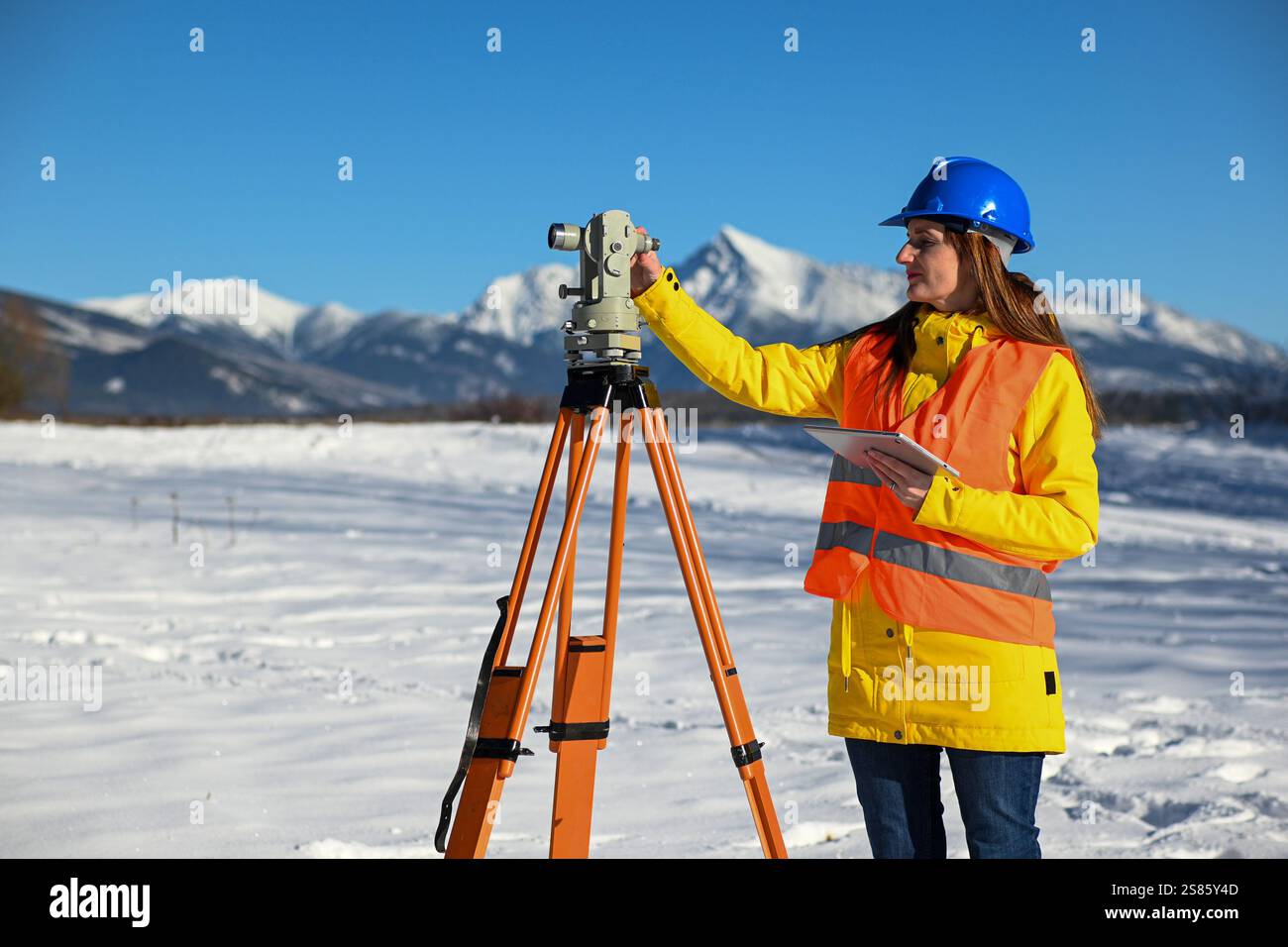 Female surveyor using theodolite and tablet computer for land surveying ...