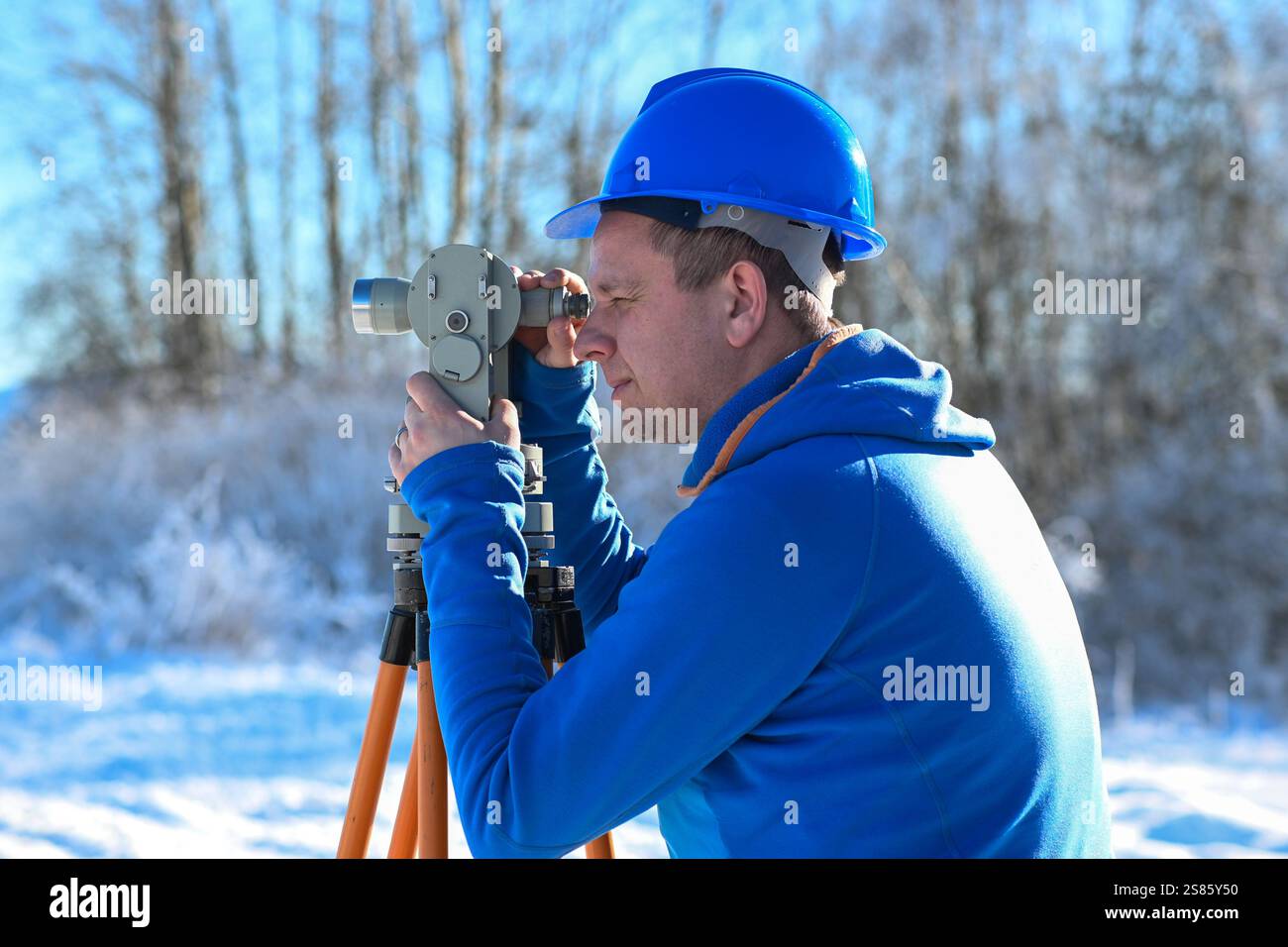 Surveyor taking measurements with theodolite in a snowy landscape ...