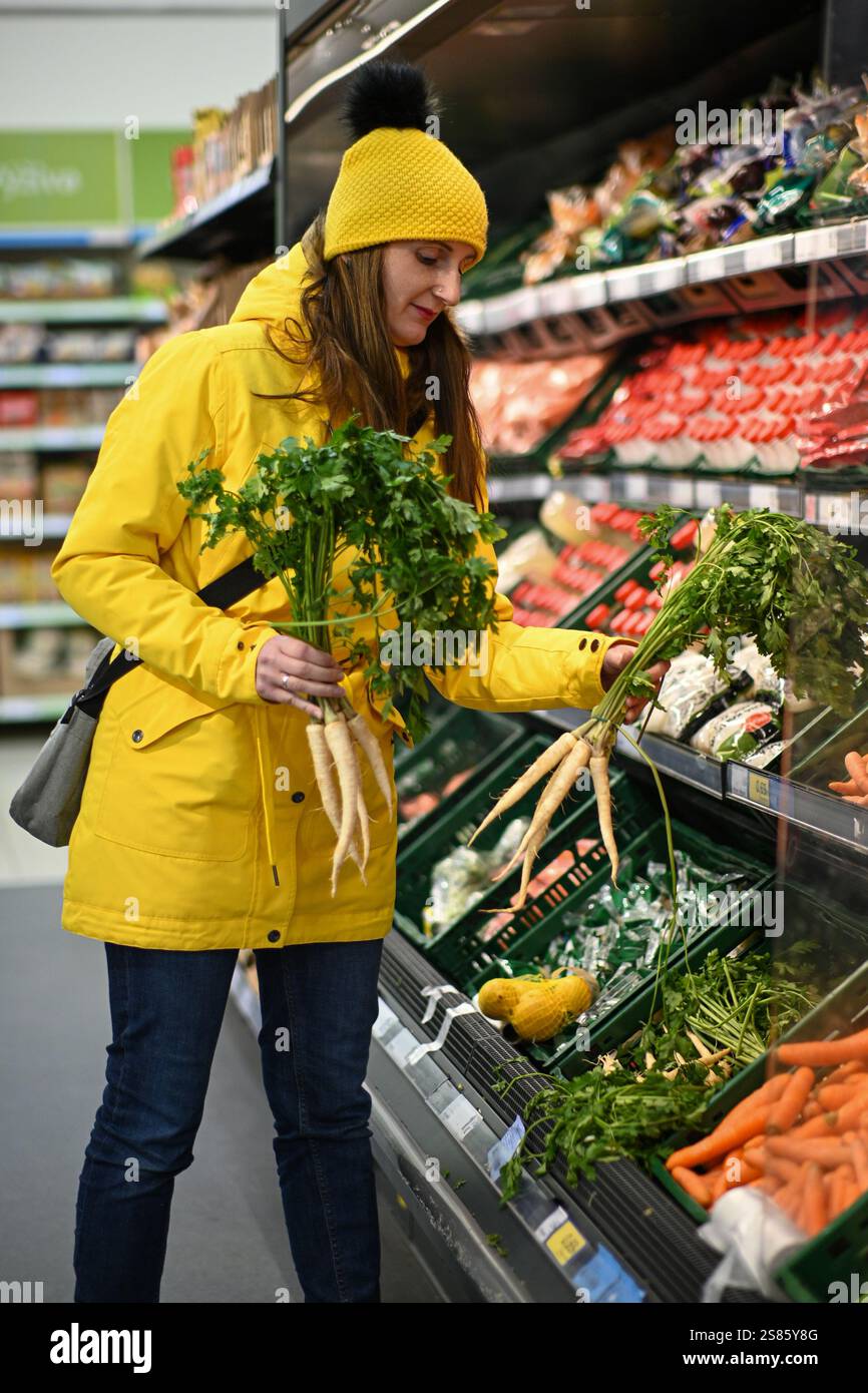 Customer selecting fresh vegetables from refrigerated shelves in ...