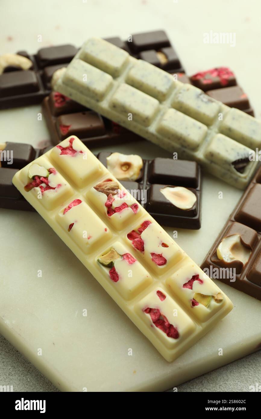 Delicious chocolate bars with different flavors on light table, closeup ...