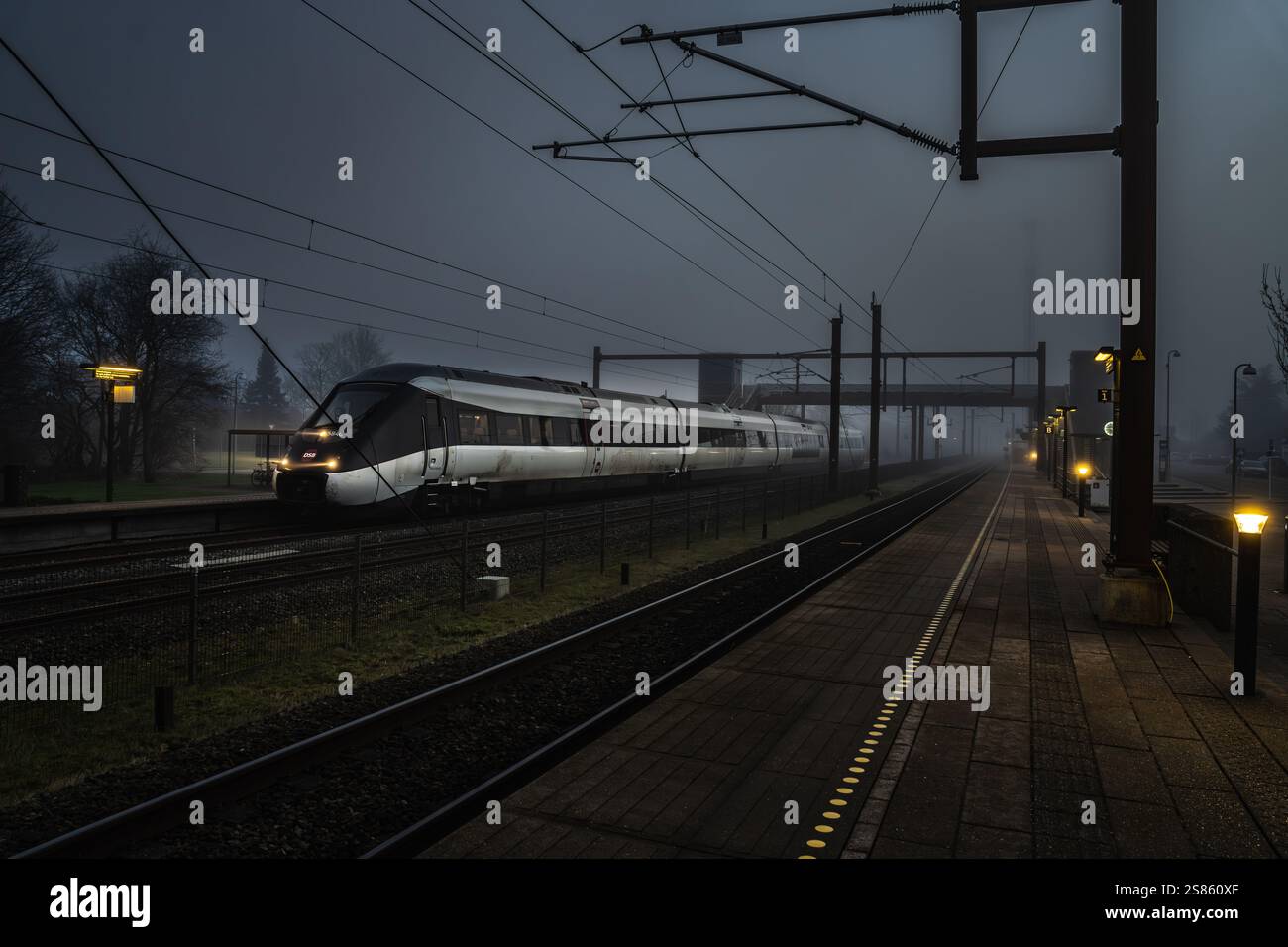 A sleek modern train stops at a deserted station platform under ...