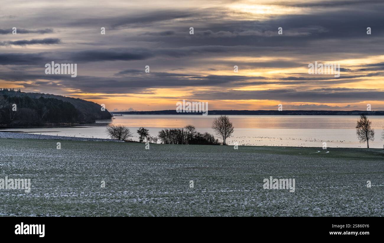 A beautiful expansive field overlooks a serene lake bordered by a dense ...