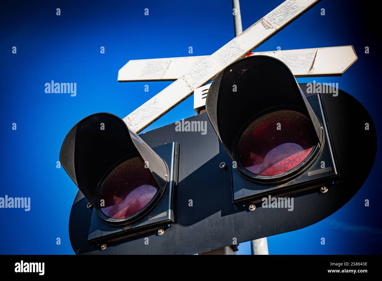 Traffic signal at railway crossing signals danger during bright sunny ...
