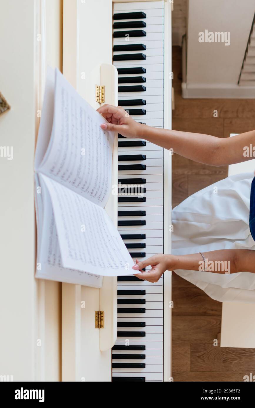 Person seated at piano holding sheet music ready to play Stock Photo ...