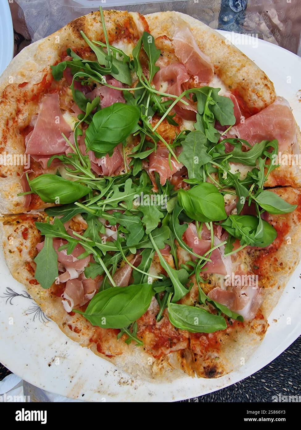 Homemade pizza wtih arugula, basil, ham, cheese, tomato sauce, golden ...