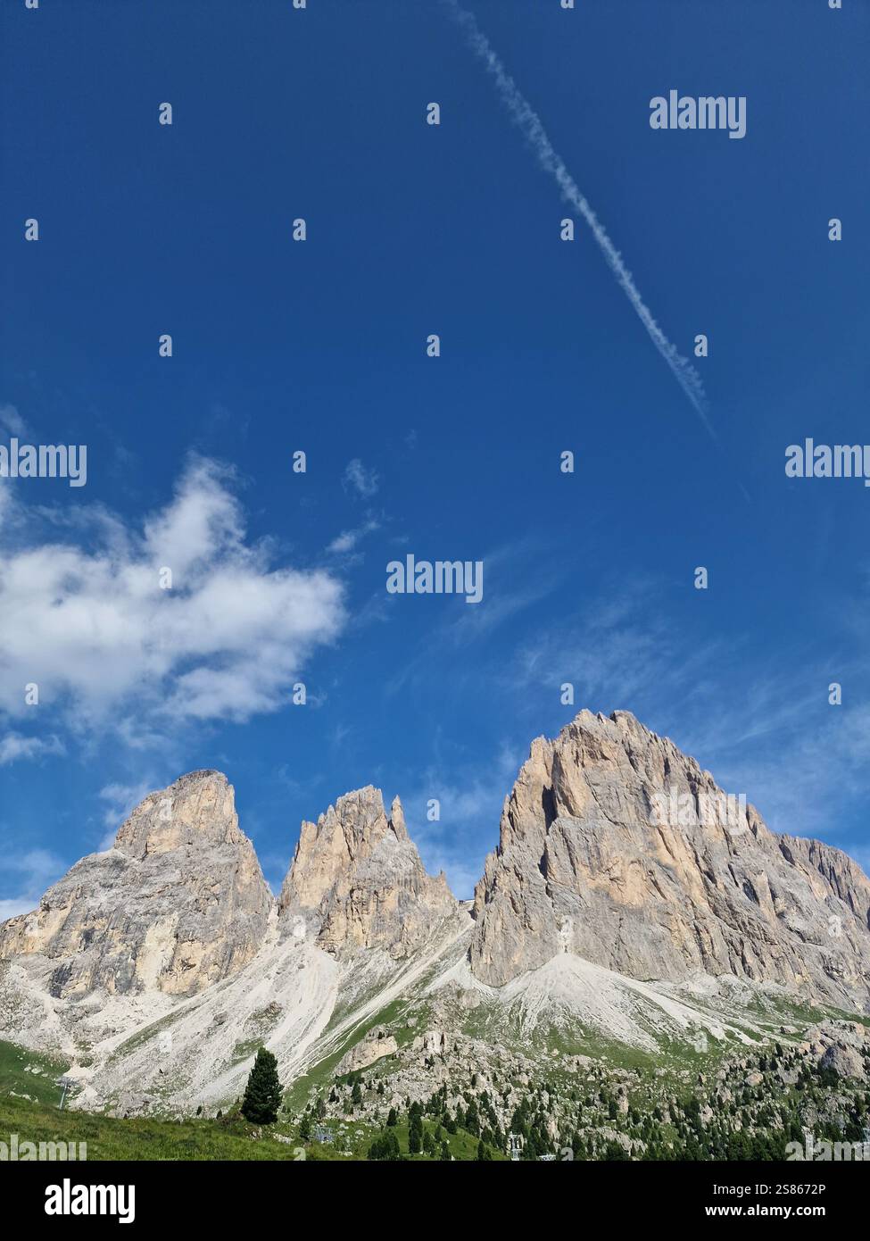 Stunning view of towering mountains under a bright blue sky with wispy ...