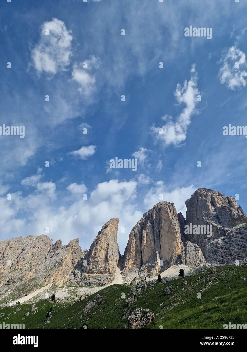 Stunning view of towering mountains under a bright blue sky with wispy ...