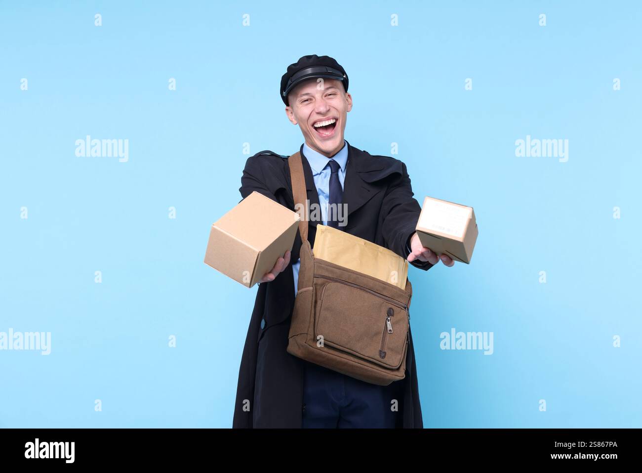 Happy postman with bag giving parcels on light blue background Stock ...