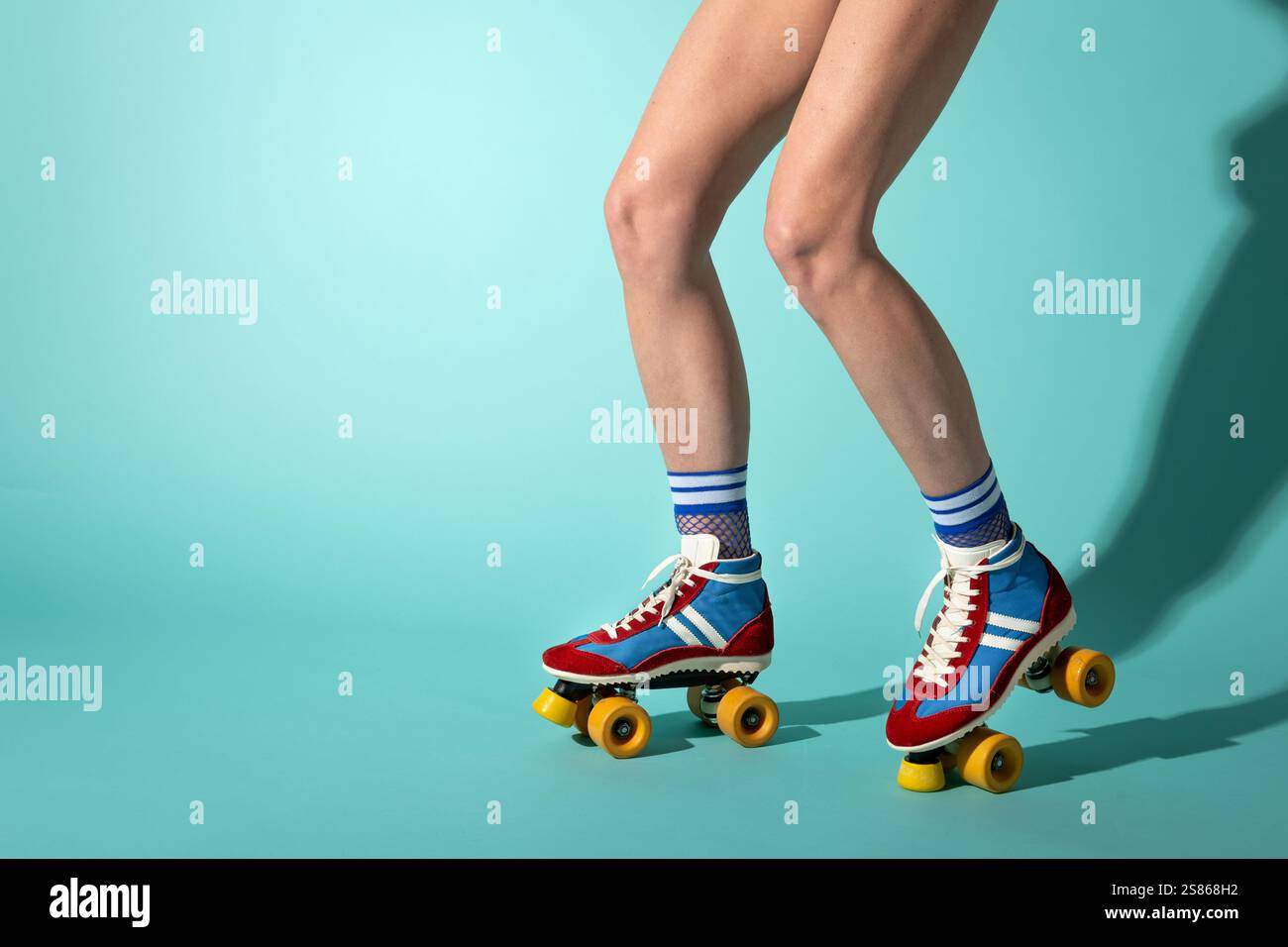 Woman wearing vintage roller skates, fishnet socks and shorts posing on ...