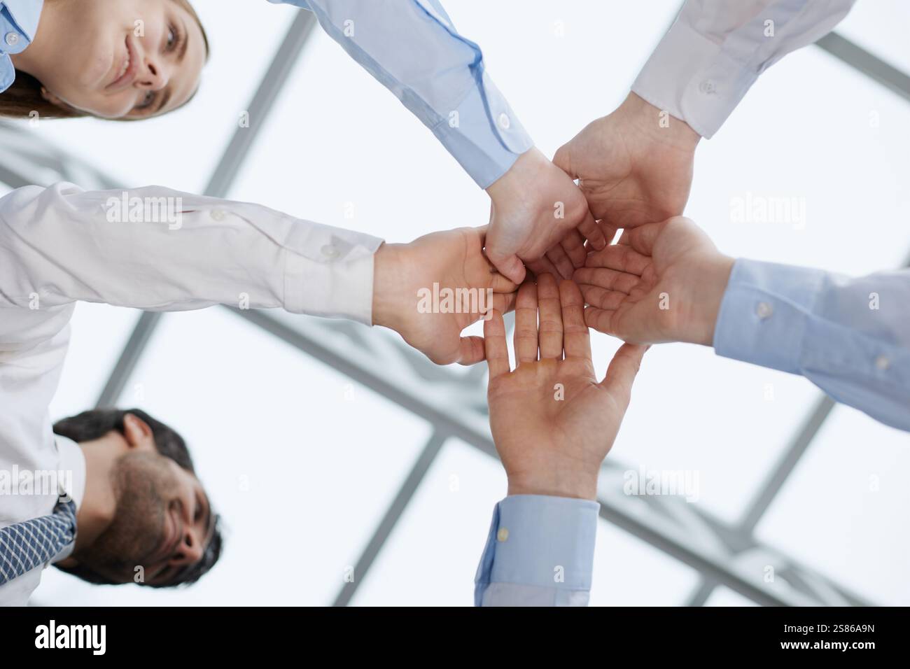 Diverse business team putting their hands together in a huddle of support and motivation Stock ...