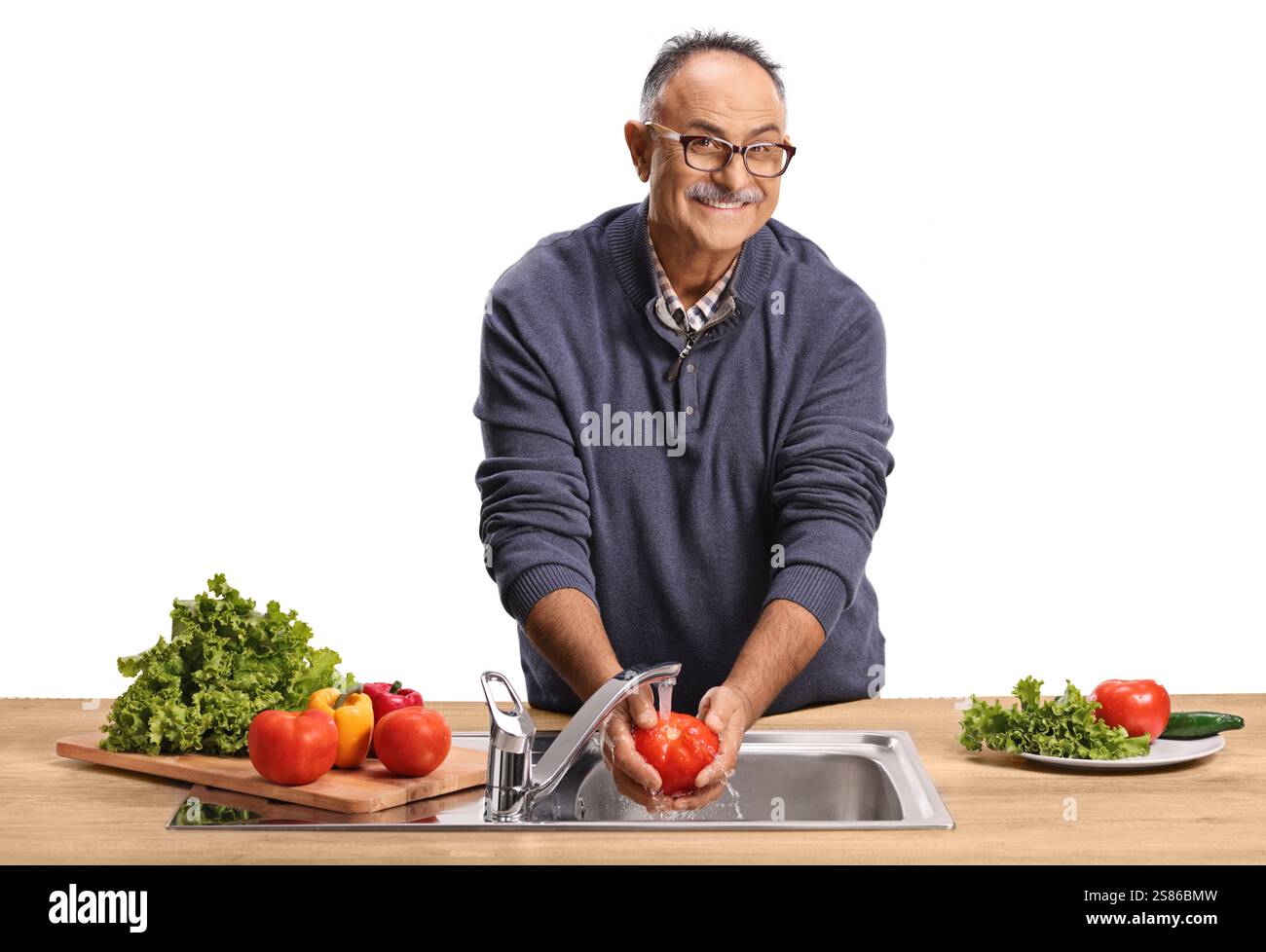 Mature man washing a tomator in a kitchen sink isolated on white ...
