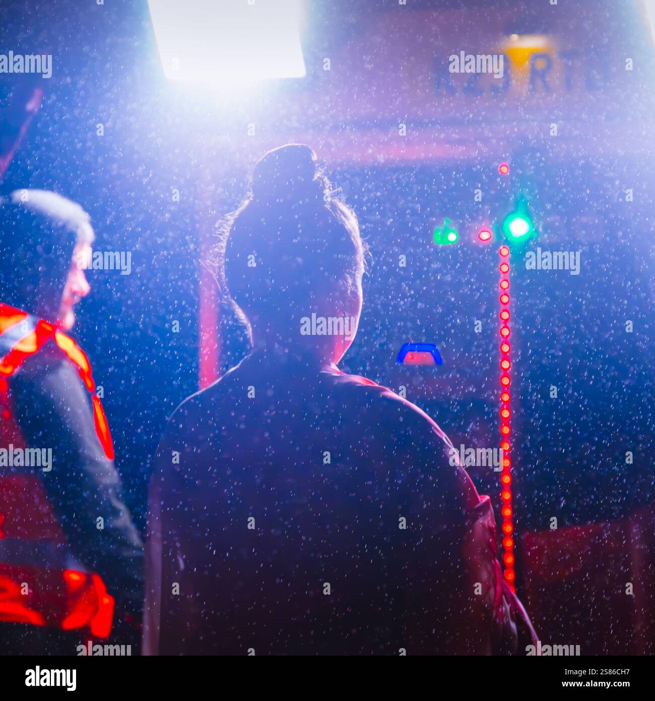 Glastonbury Carnival Performer Silhouette in Pouring Rain lit by bright ...