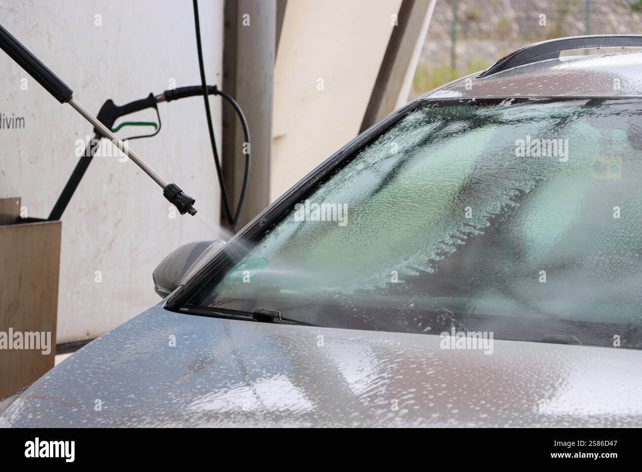 The car is washed at a car wash. The pressurized water jet cleans the ...