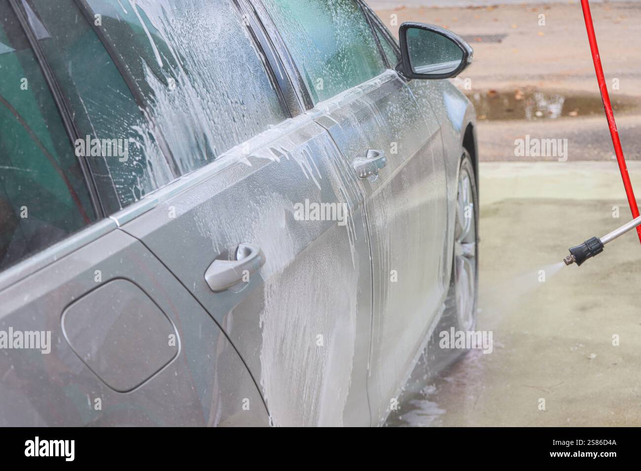 The car is washed at a car wash. The pressurized water jet cleans the ...