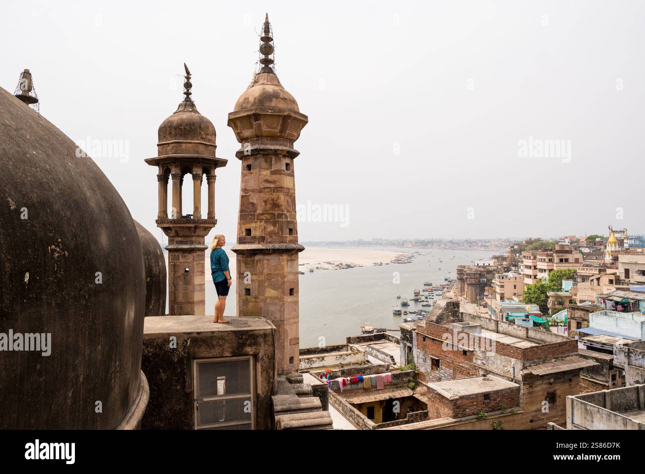 Young woman standing on the mosque roof overlooking Varanasi old town ...