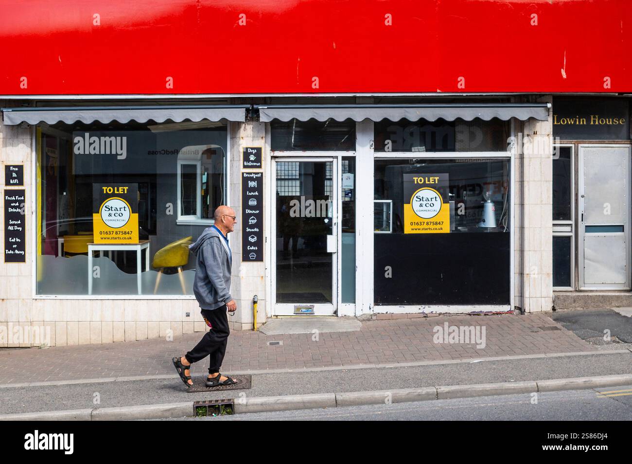 A man walking past a closed shop store available to let in Newquay Town ...