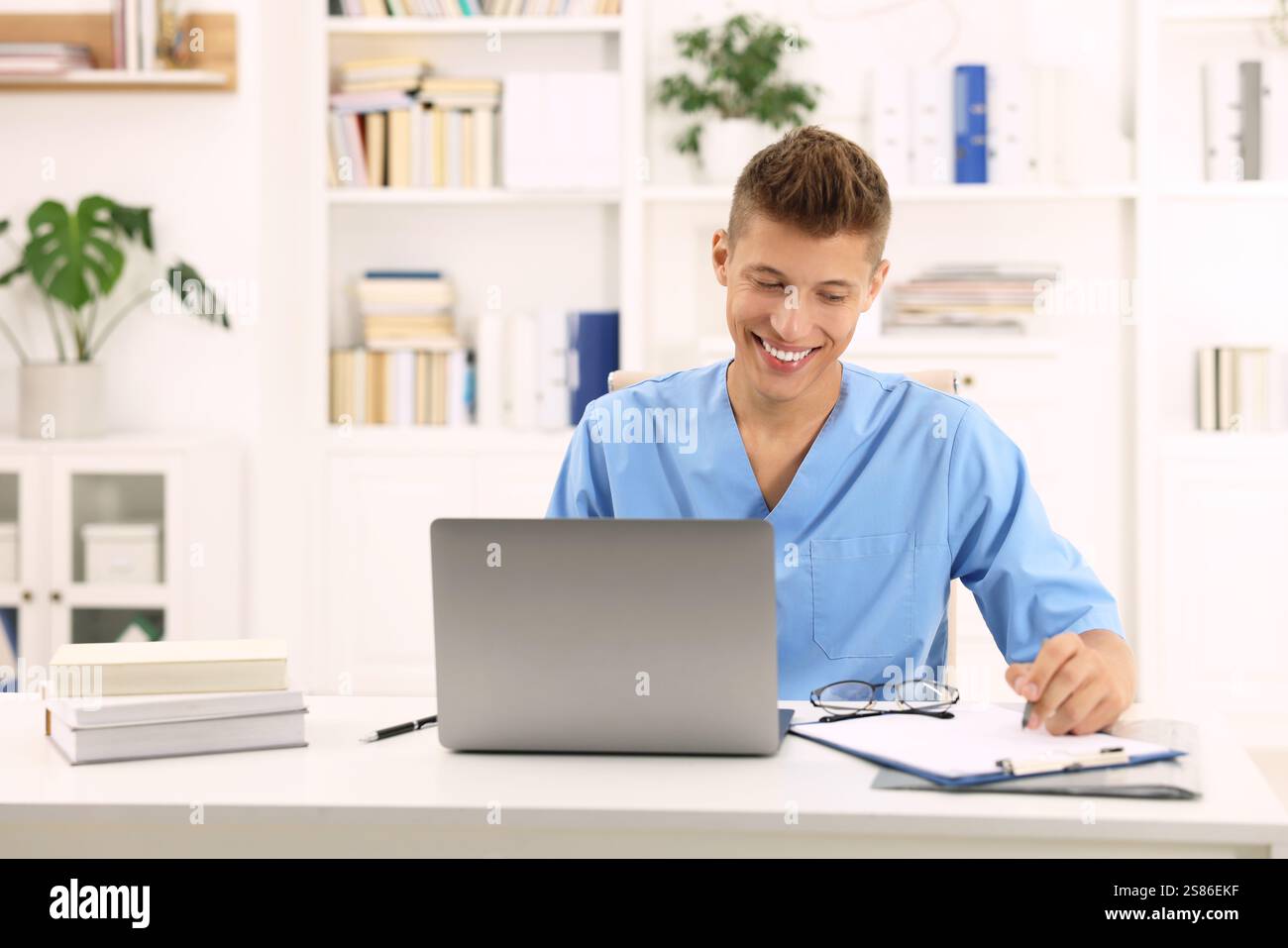 Medical student in uniform studying at table indoors Stock Photo - Alamy