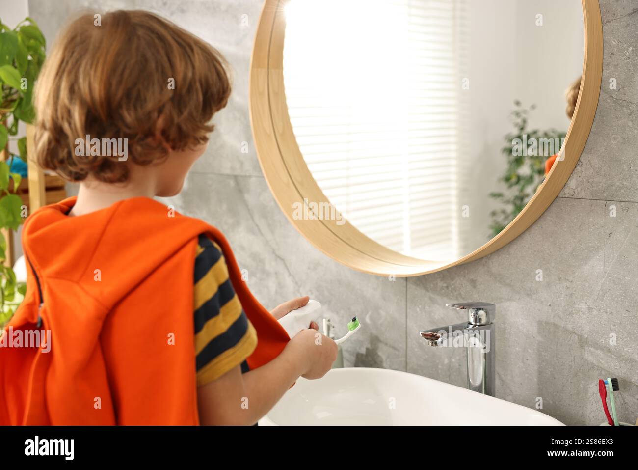 Cute boy applying paste on toothbrush in bathroom Stock Photo - Alamy