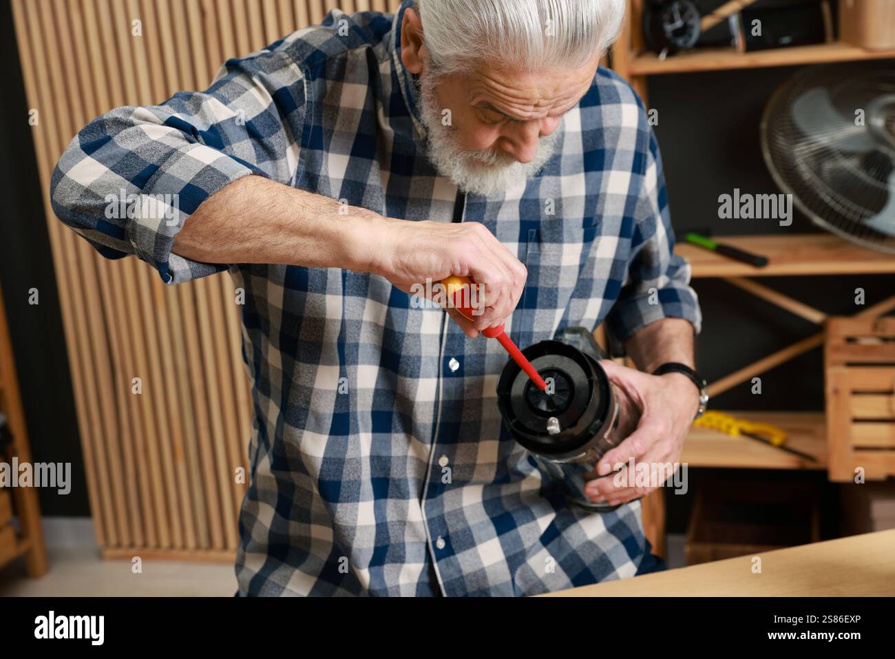 Relaxing hobby. Senior man repairing blender with screwdriver in ...