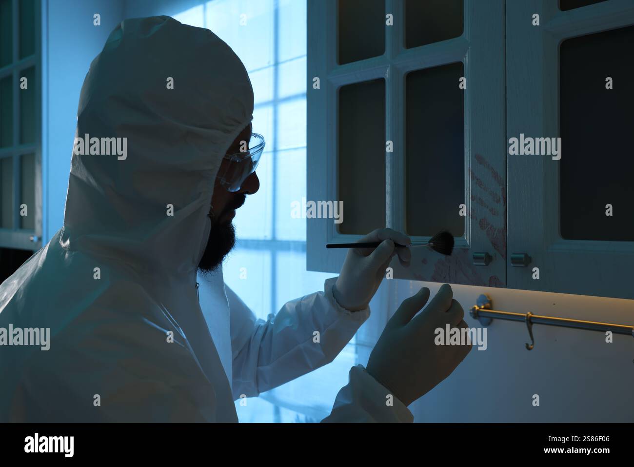 Forensic expert taking fingerprints from cupboard with brush at crime ...