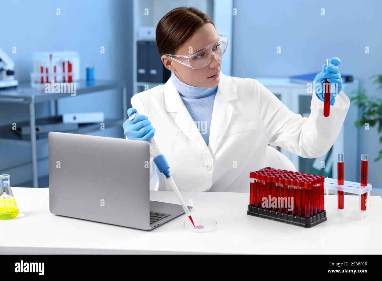 Laboratory testing. Doctor holding test tube with blood sample at table ...