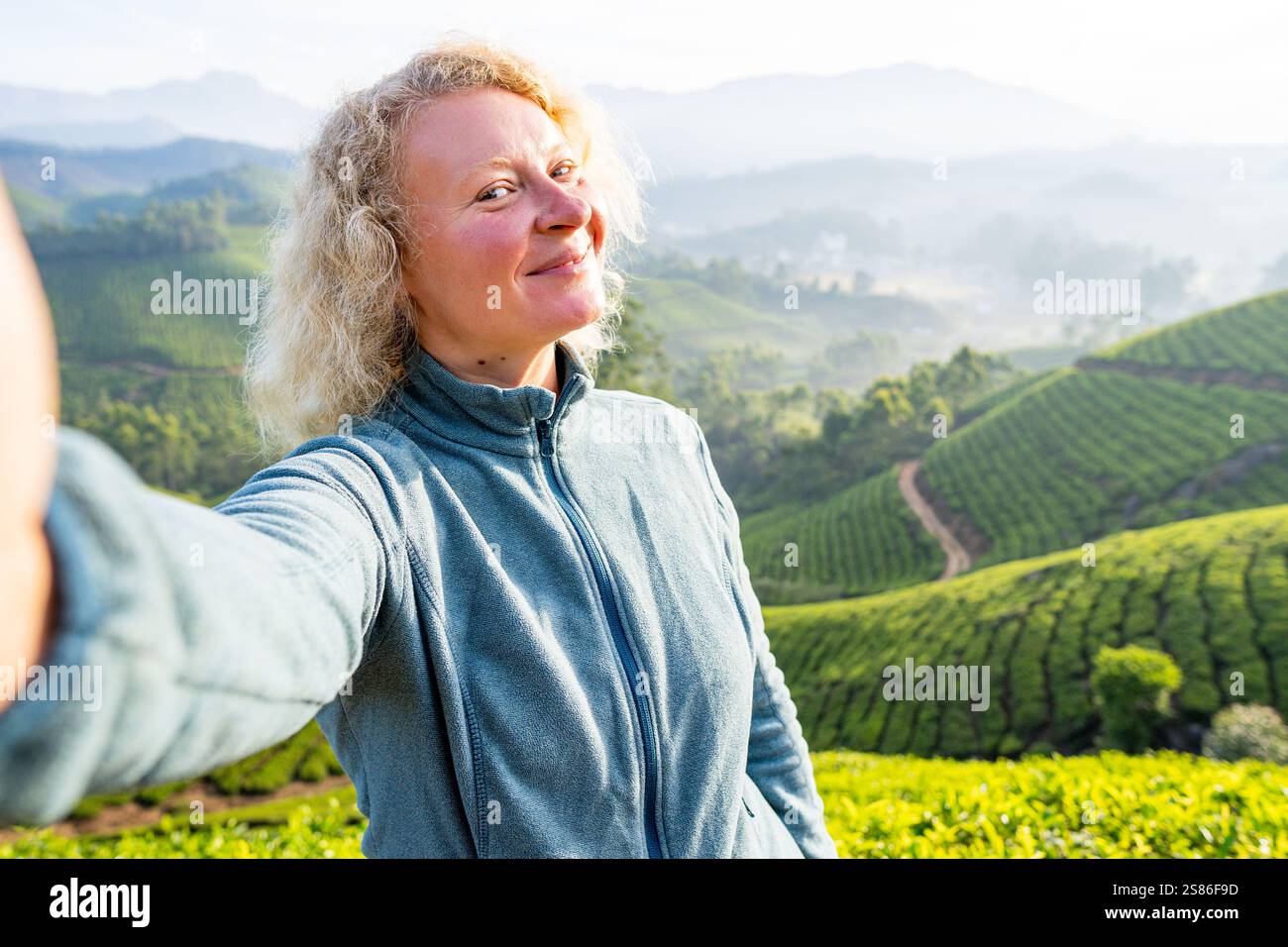 Young smiling woman taking selfie with tea plantations in Munnar. Eco ...