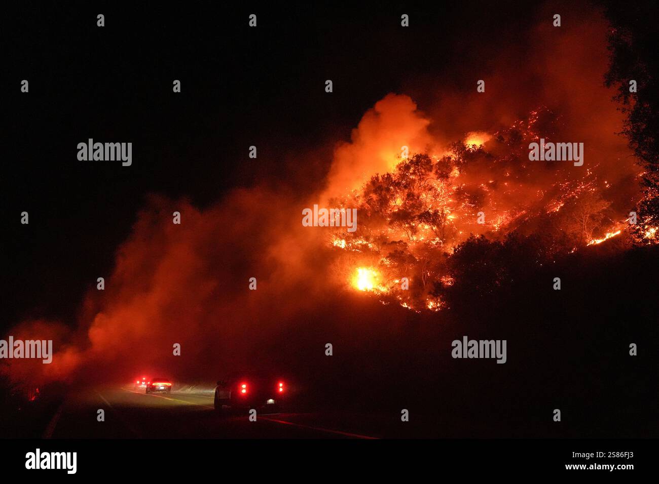 Vehicles pass through smoke from the Lilac Fire in Bonsall, Calif ...