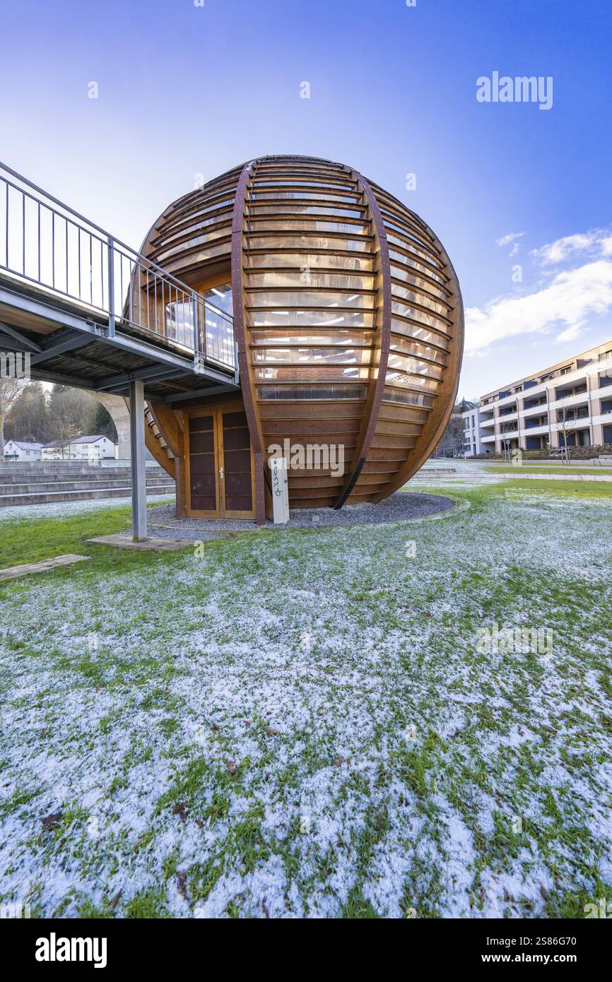 Modern wooden ball with adjoining metal bridge in front of a blue sky ...