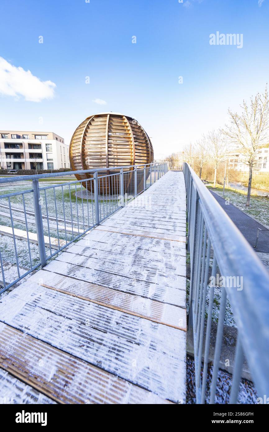 Wooden ball structure next to a wooden path with metal railing under a ...