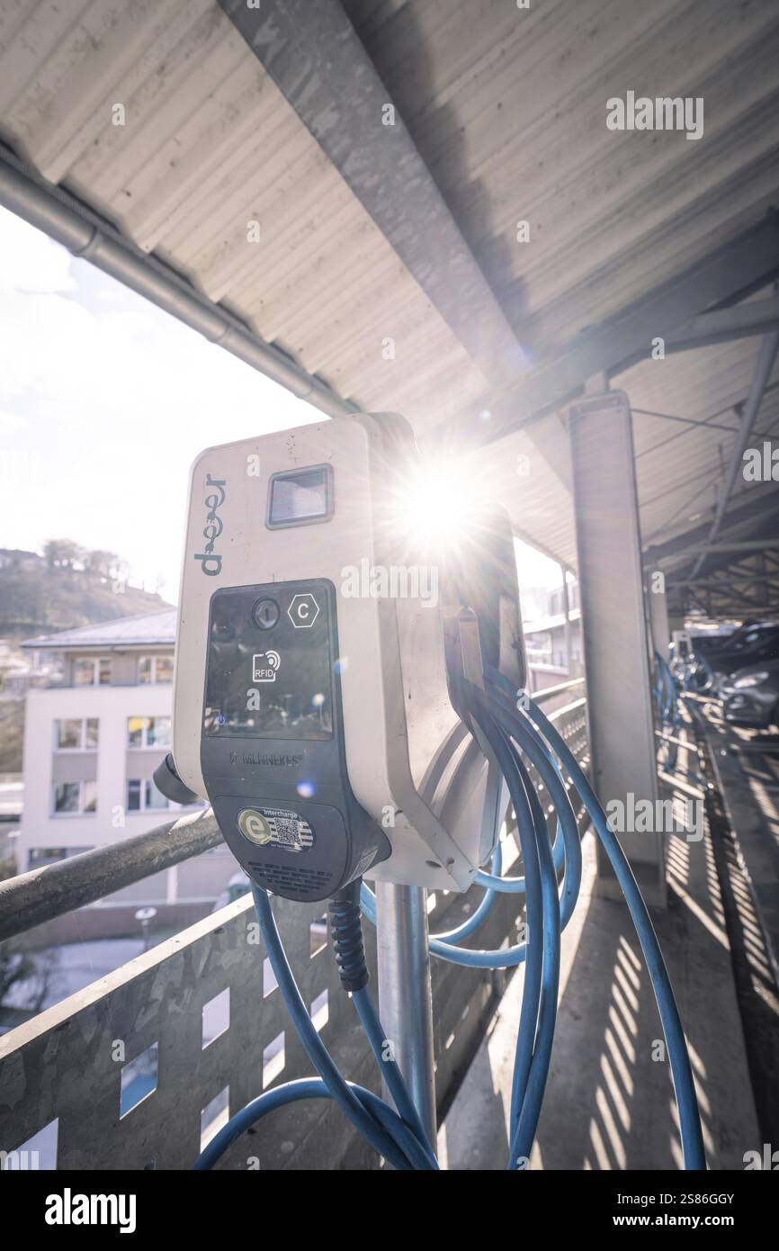 Electric charging station illuminated by sunlight, with blue cables ...