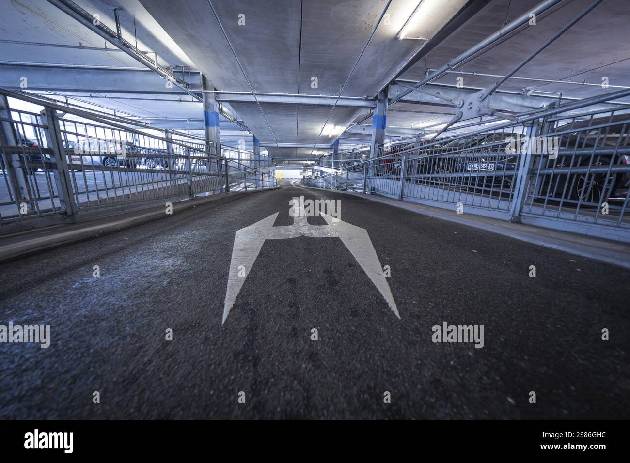 View into a multi-storey car park with central directional arrow on asphalt and concrete ...