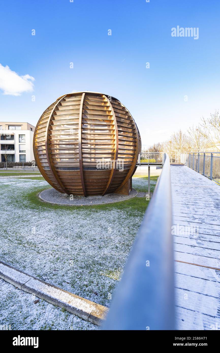 Large wooden sphere structure on grass, in the background modern ...