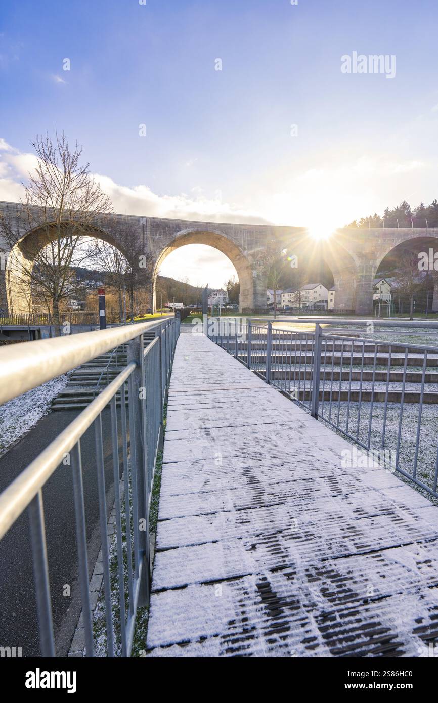 Wooden walkway with snow under a viaduct at dusk, with clear sky and ...