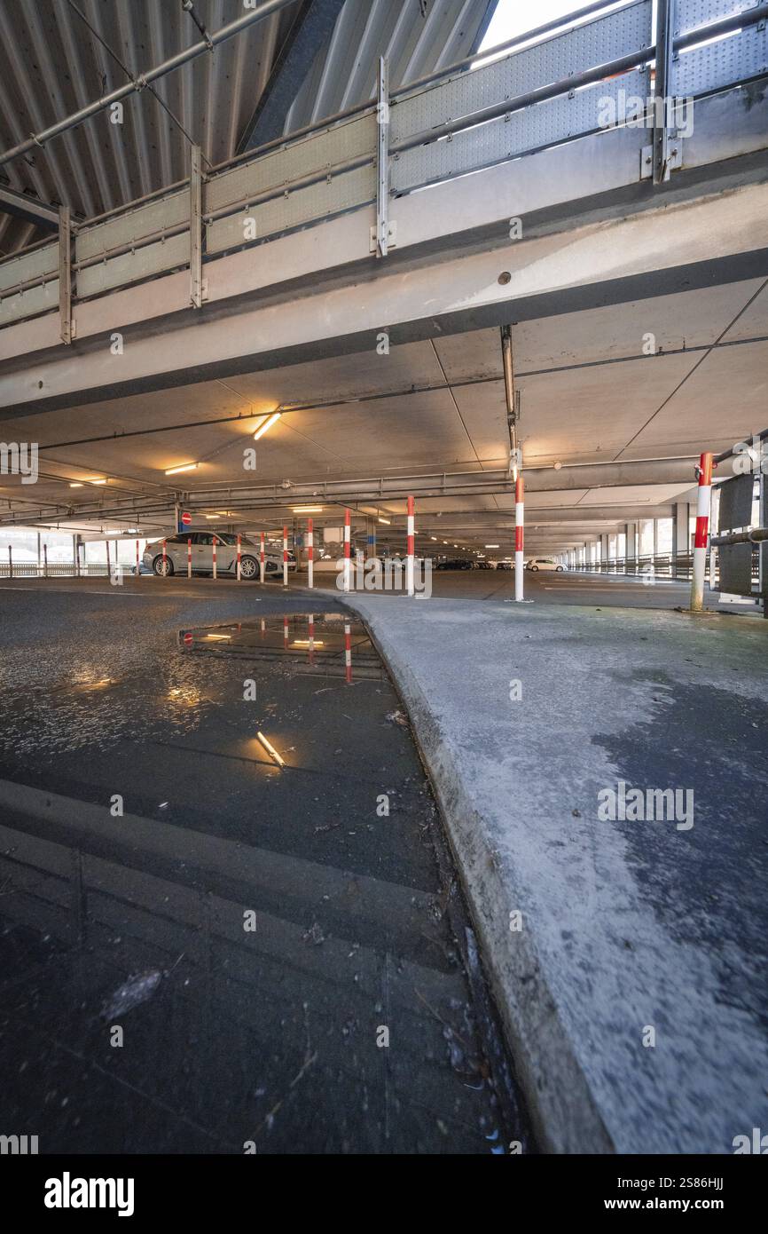 Puddle of water reflects the interior of a multi-storey car park with ...