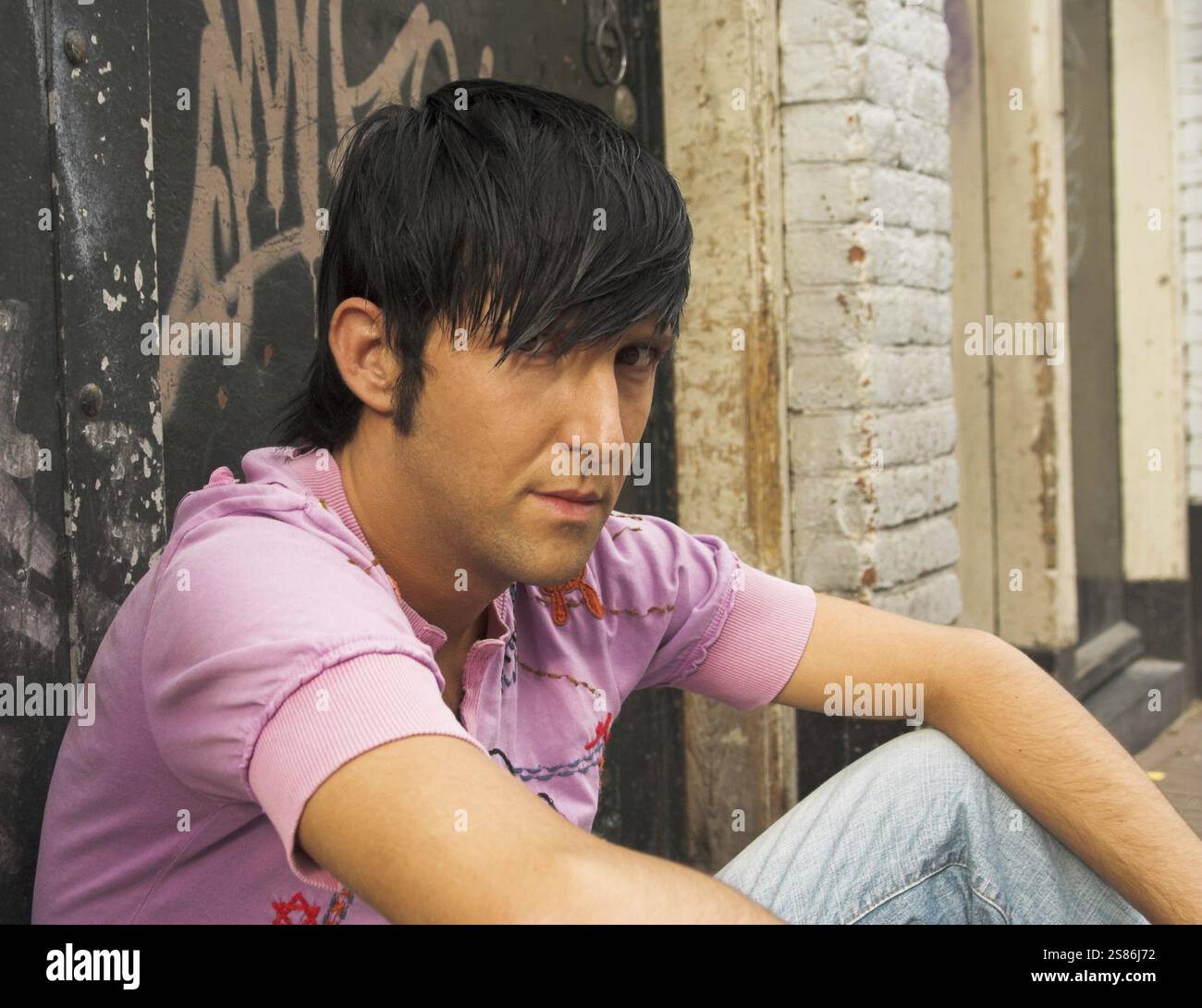Self-confident bad guy sitting on the ground in ghetto Stock Photo - Alamy