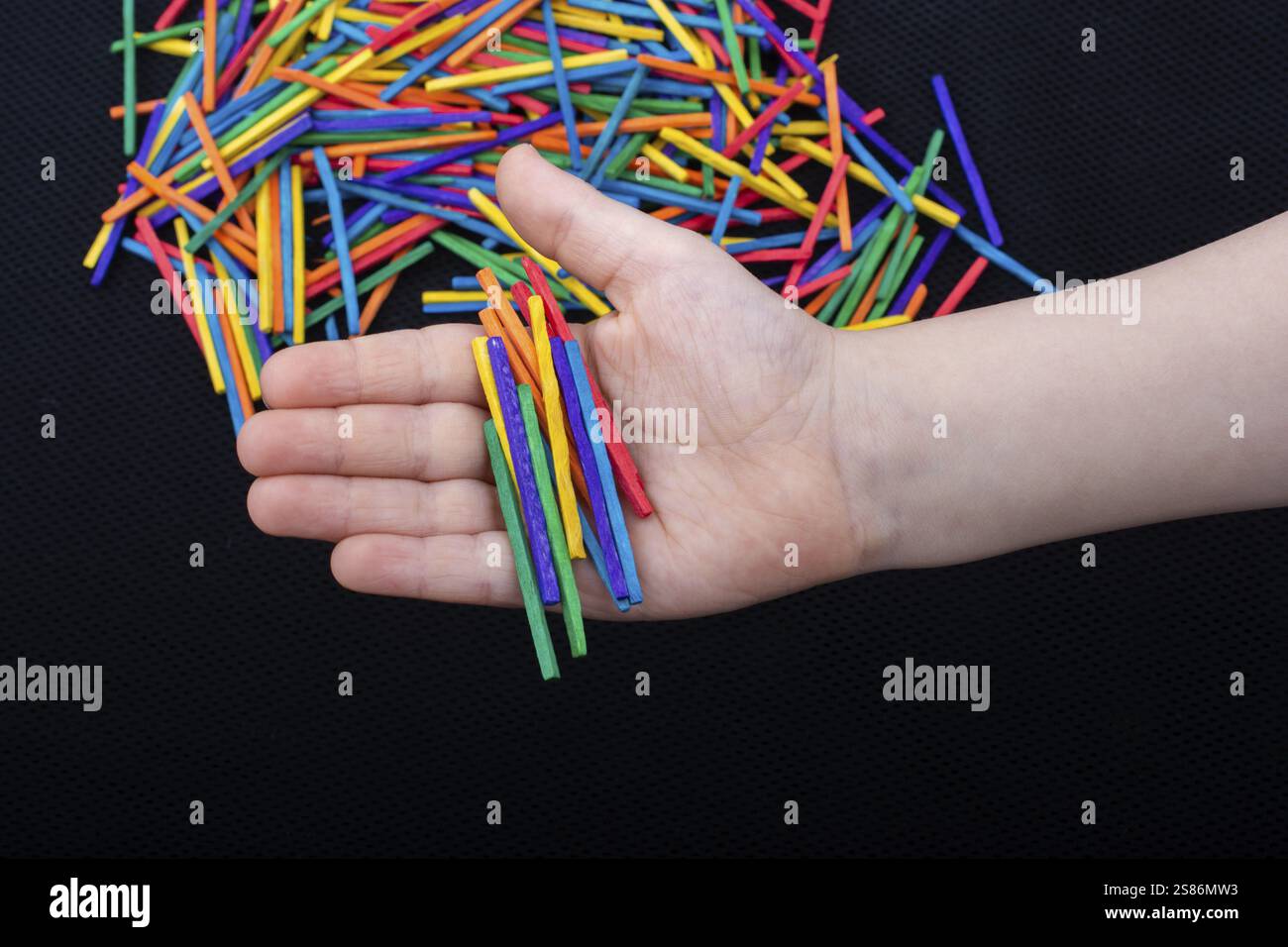 Kid playing with coloured wooden sticks for creativity on white ...