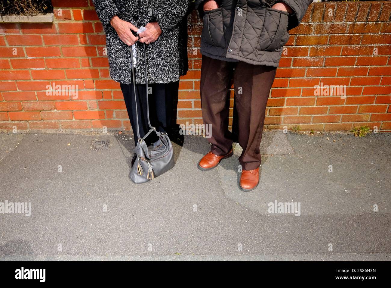 Man woman husband wife waiting pavement bus legs feet Stock Photo - Alamy